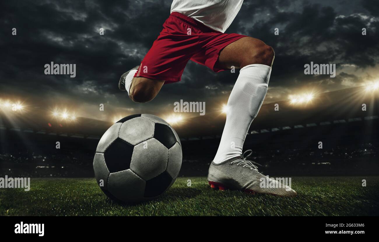 Cropped male soccer, football player kicking ball at the stadium during ...