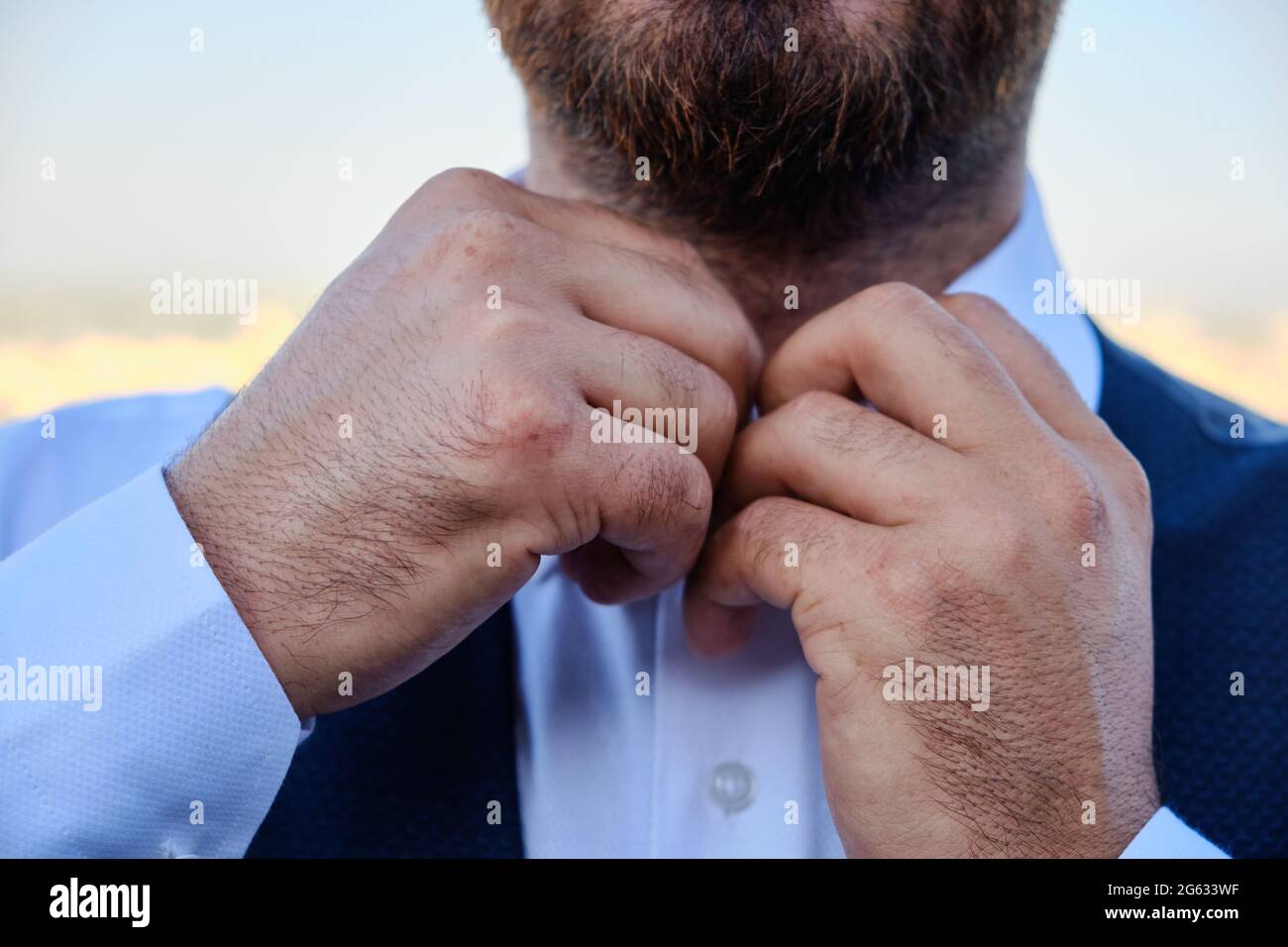 Man buttons his white shirt up Stock Photo - Alamy