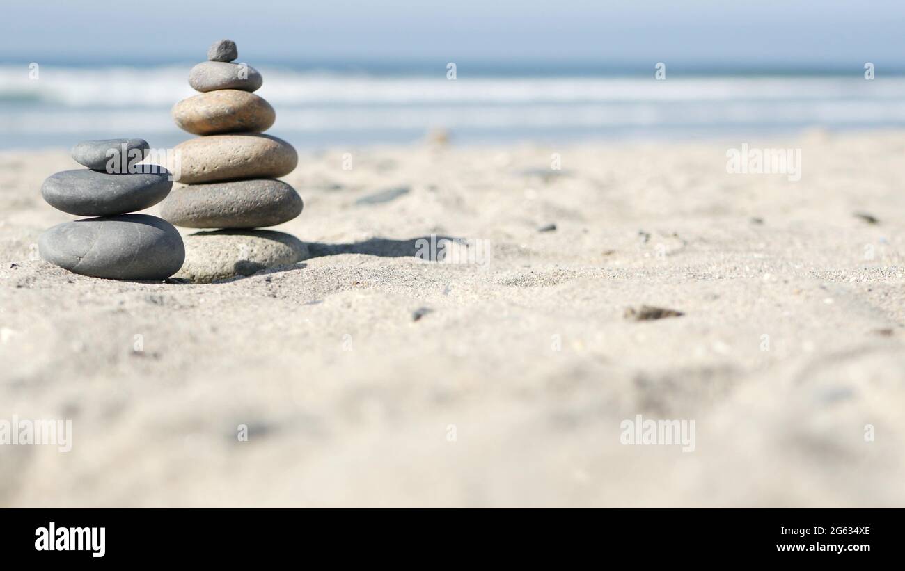 Rock balancing on ocean beach, stones stacking by sea water waves ...