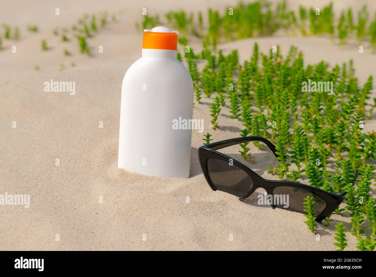 Sunscreen protection lotion and sunglasses in the sand on a sunny day ...