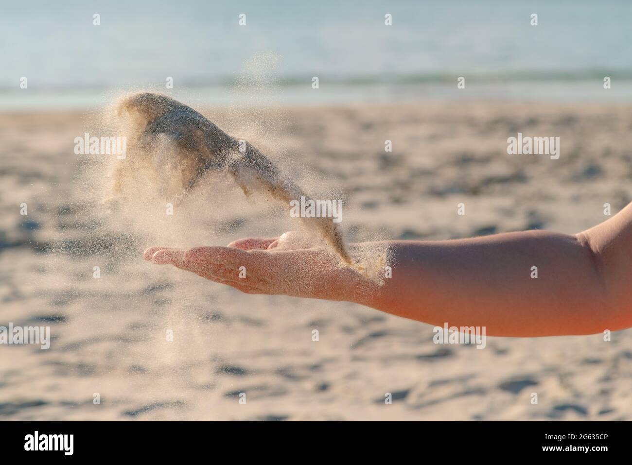Close up of sand pouring from the hand on the beach on a sunny summer ...