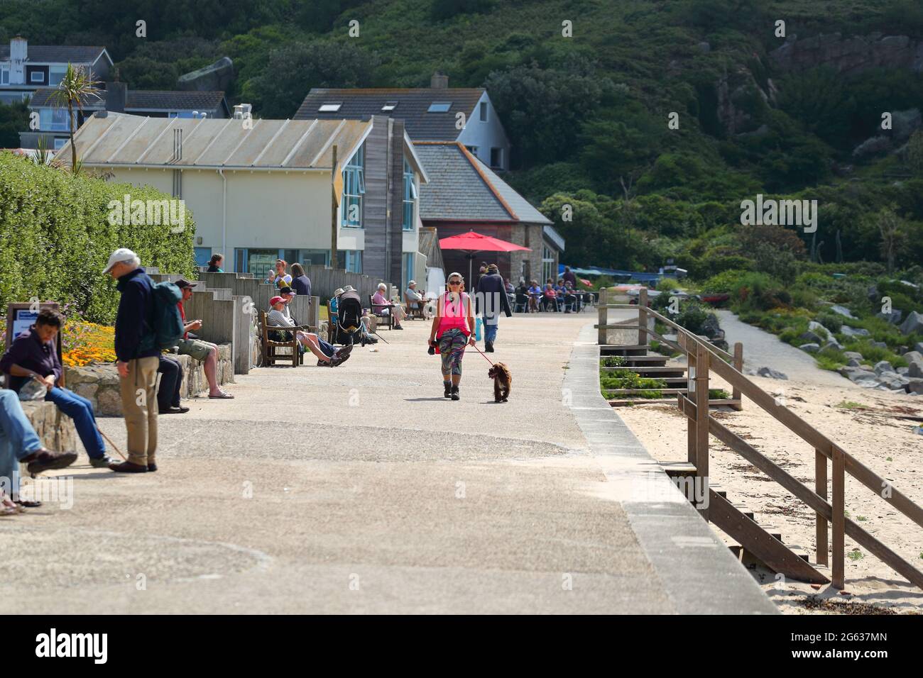Visitors enjoy a sunny day on the promenade at Porthcressa beach at ...