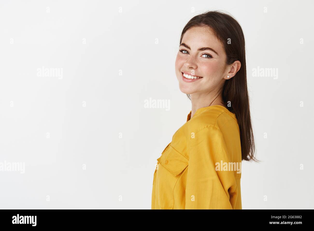 Young confident woman turn head at camera, looking happy and smiling ...