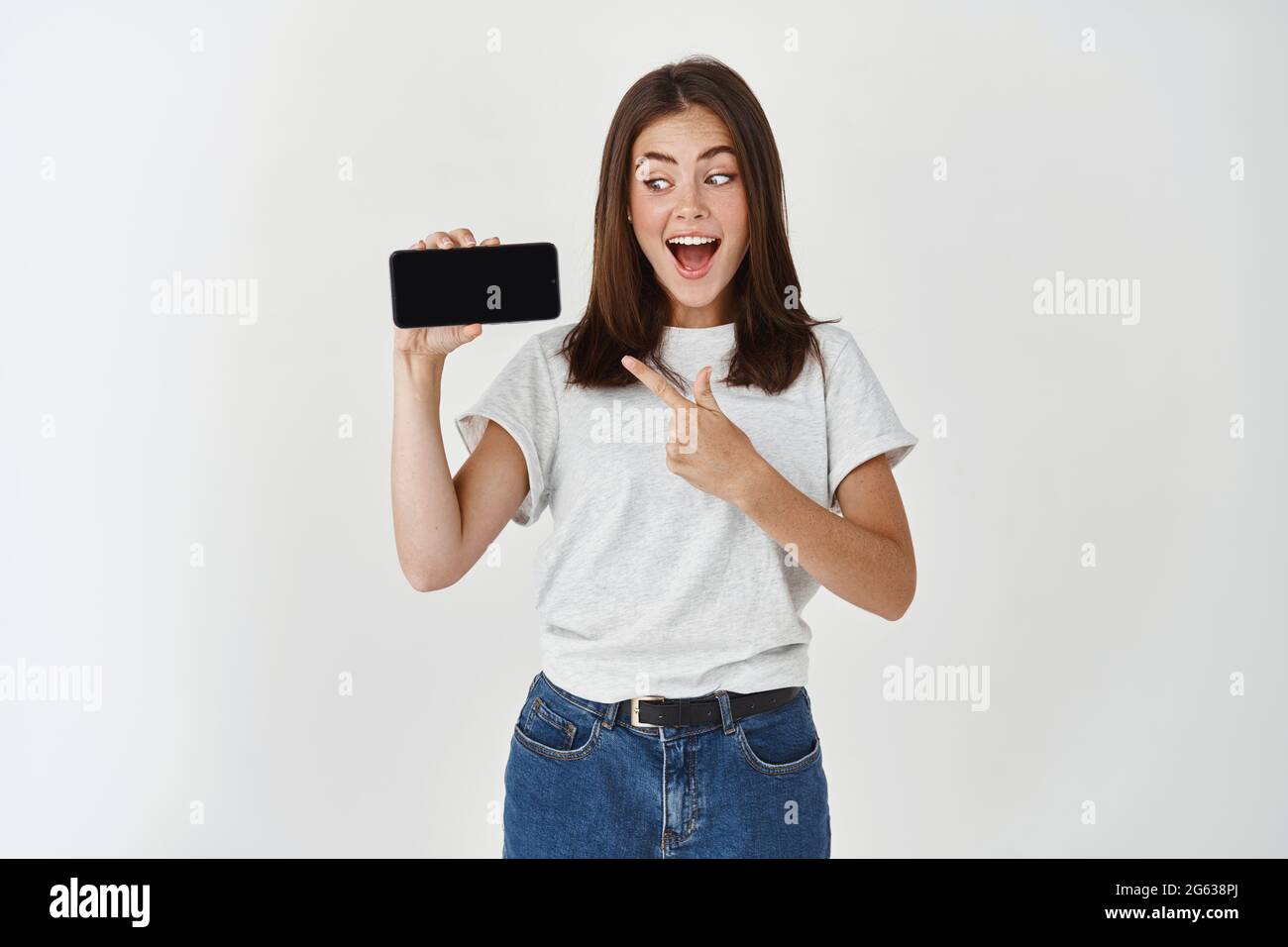 Excited smiling woman holding smartphone, showing blank cellphone ...