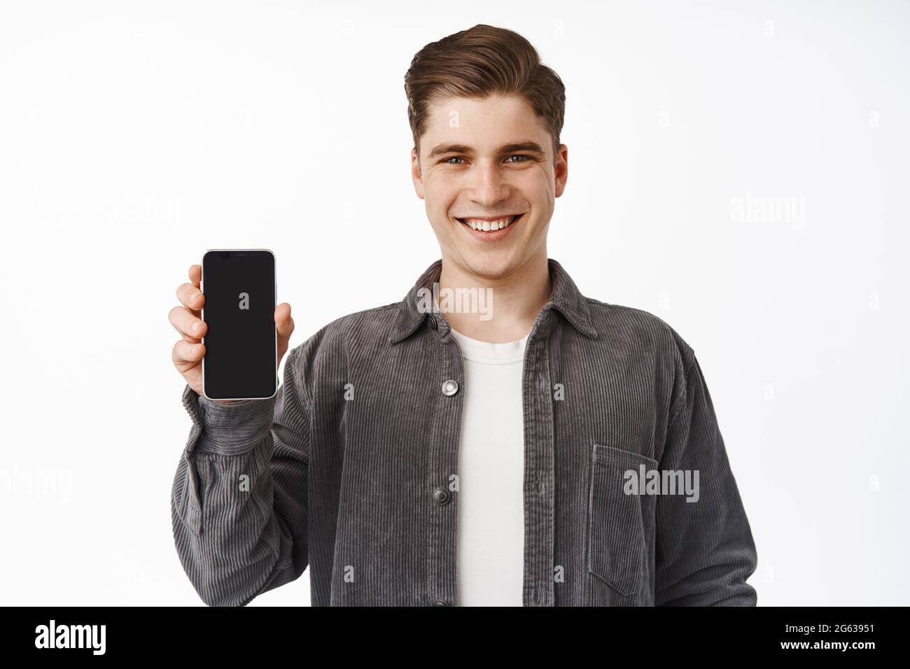 Close up of smiling caucasian guy, young man shows smartphone screen ...