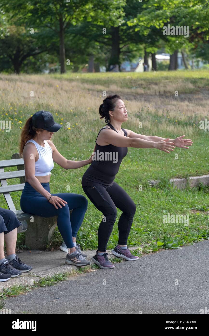 A woman working with her trainer on the proper form for deep knee bend ...