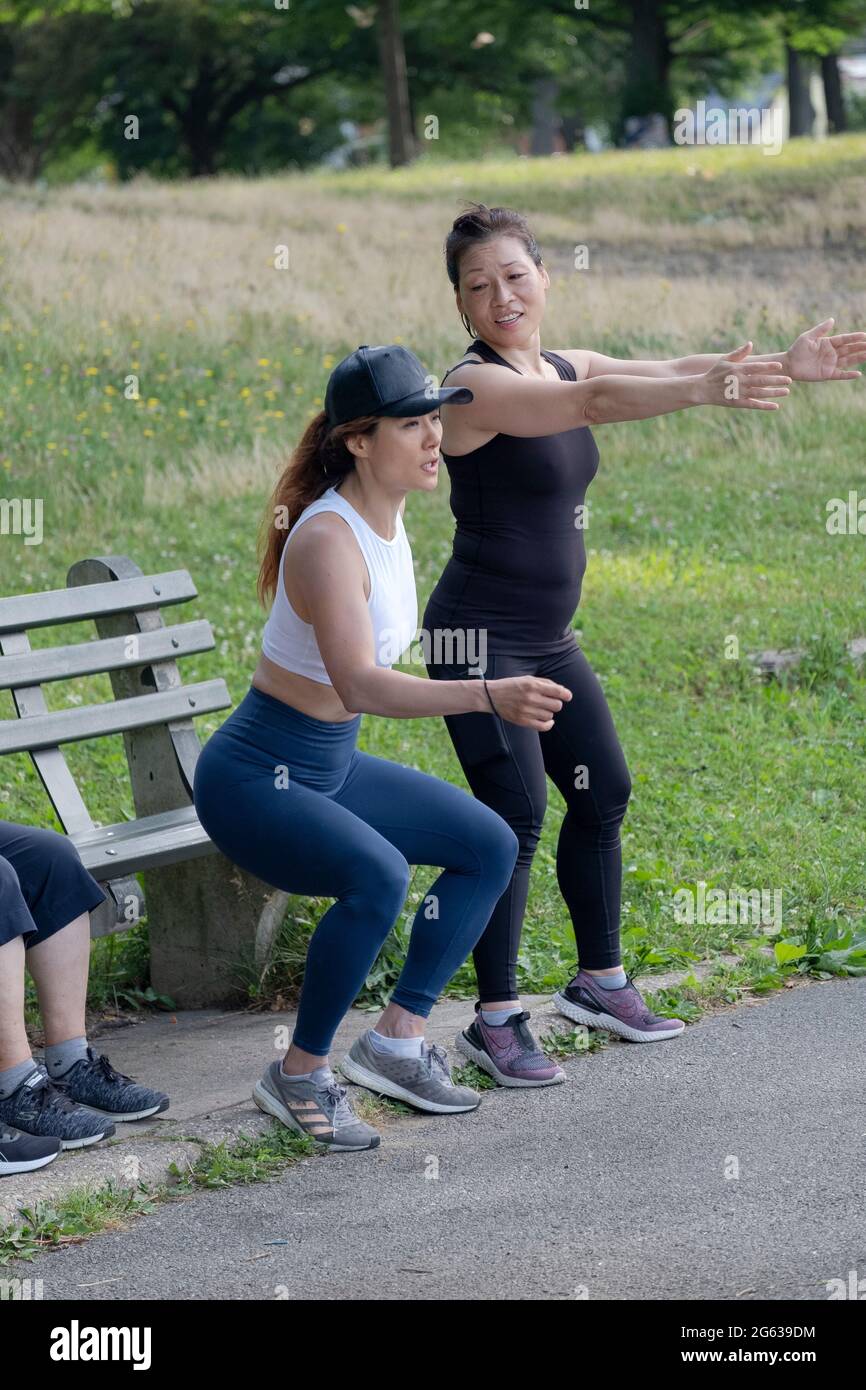 A woman working with her trainer on the proper form for deep knee bend ...