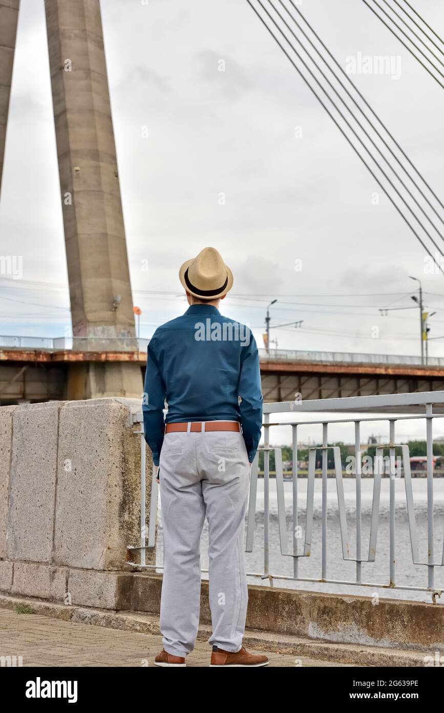 Rear view of thoughtful man, businessman looking at cityscape and river ...