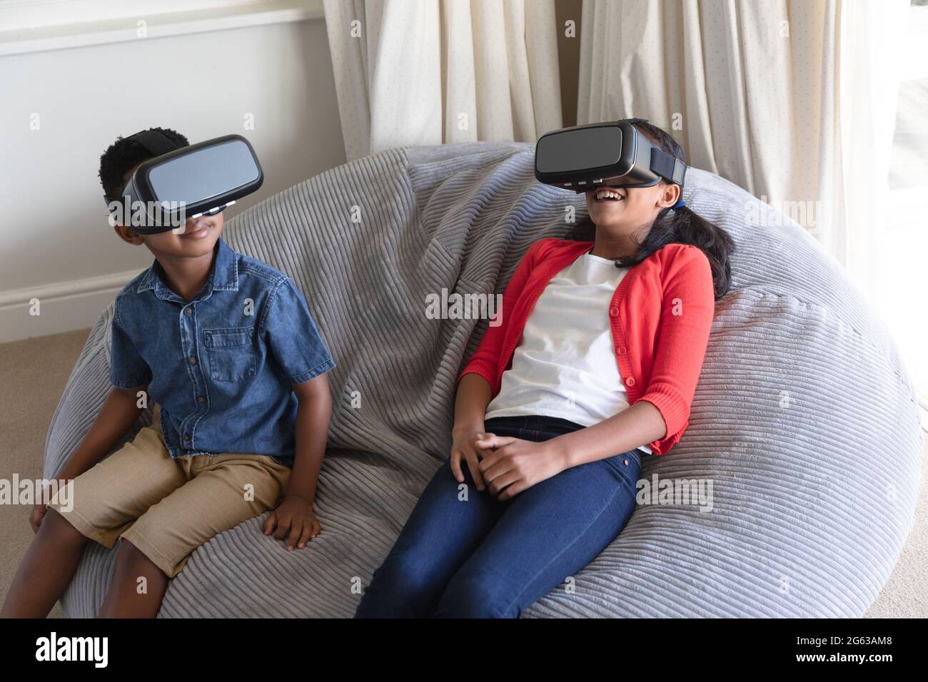 Happy african american boy and girl using vr headsets and smiling at ...