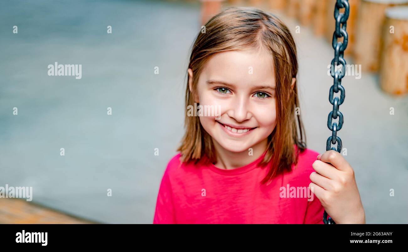 Little girl sitting on chain swing at playground Stock Photo - Alamy