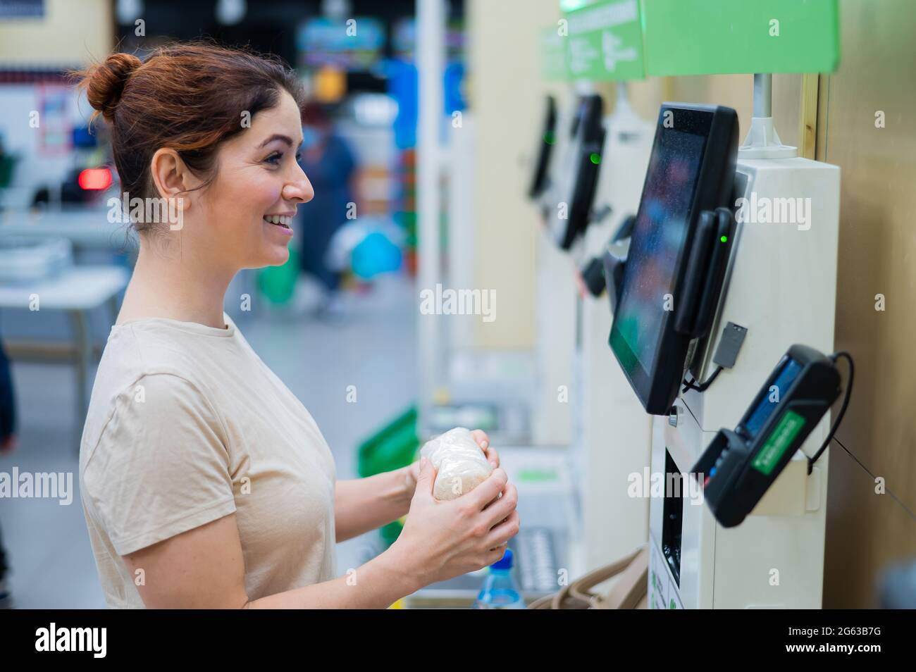 Caucasian woman uses a self-checkout counter. Self-purchase of ...
