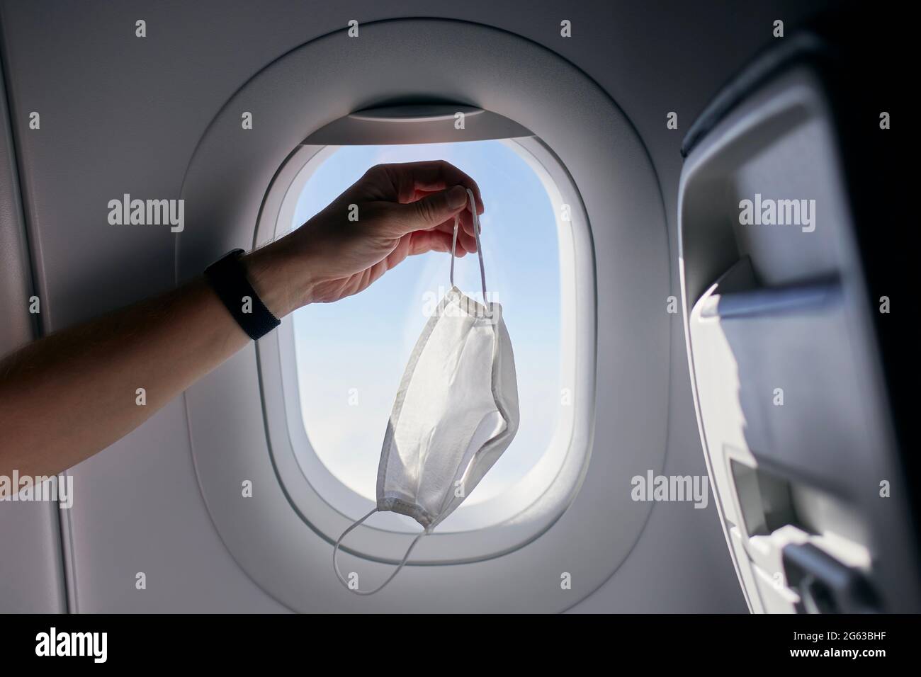 Hand holding protective face mask against airplane window. Themes ...