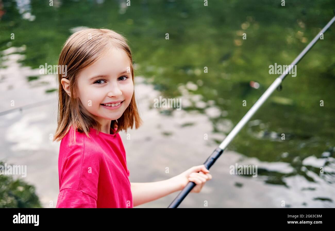 Little girl holding fishing rod on pond background Stock Photo - Alamy