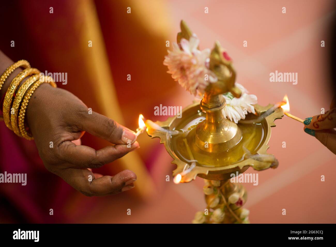 Woman lighting a traditional brass oil lamp during a Hindu wedding ...