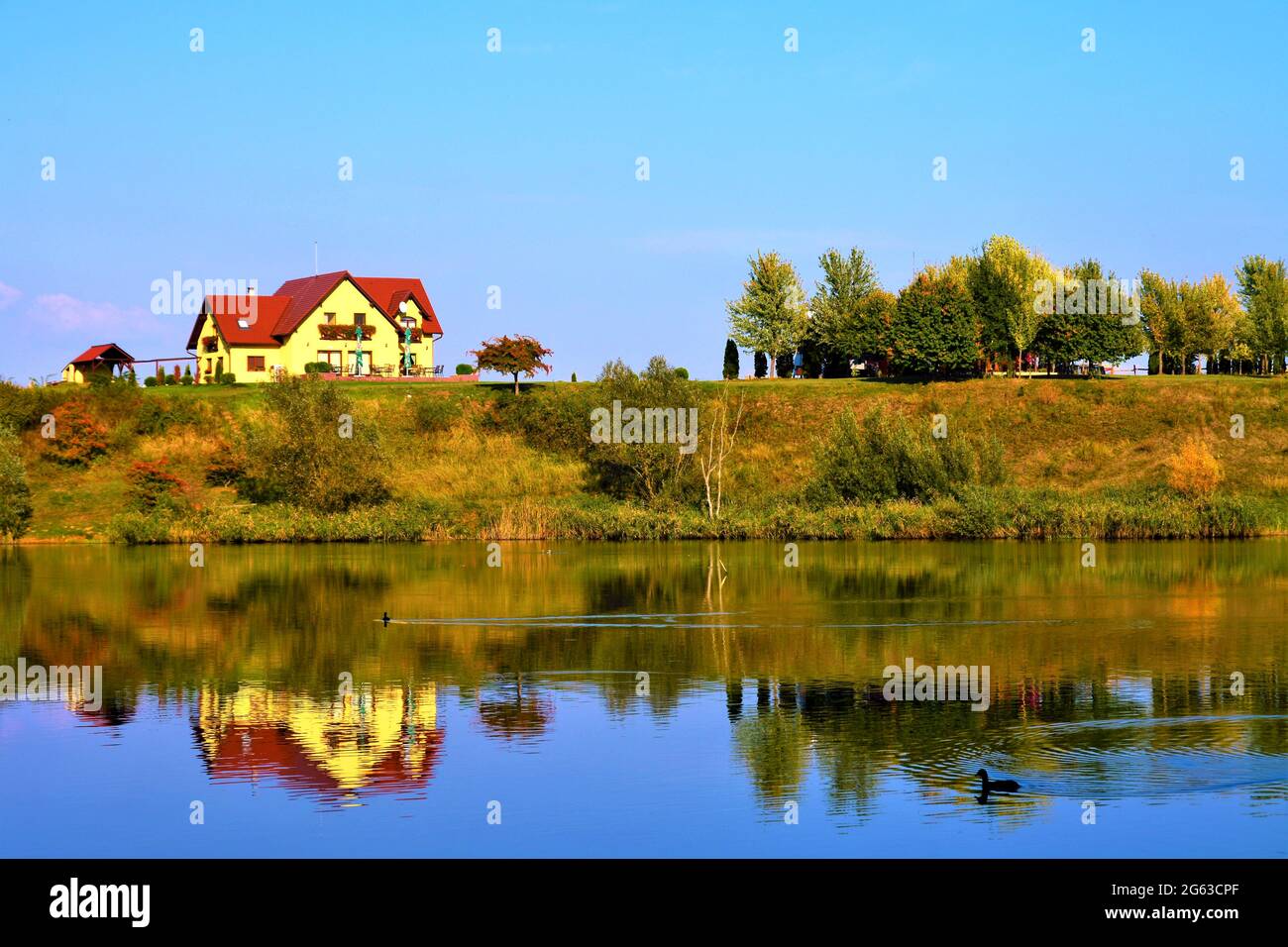 House on the shore reflected in the water surrounded by trees Stock ...