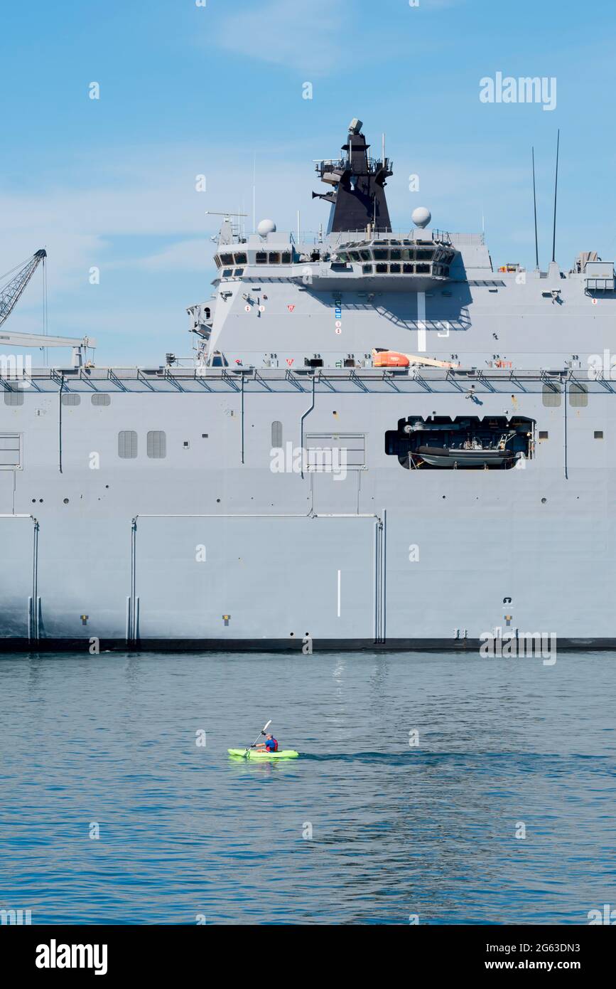 A kayaker paddles beside the Royal Australian Navy landing helicopter ...