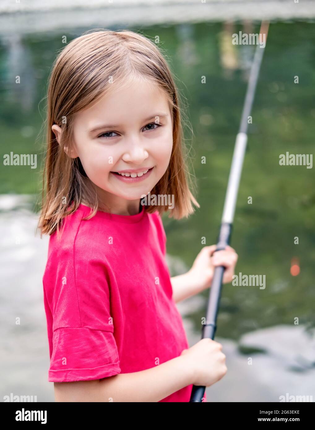 Little girl holding fishing rod on pond background Stock Photo - Alamy