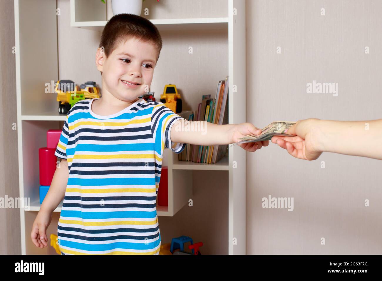 A small child boy takes dollar bills from the hands of an adult parent ...