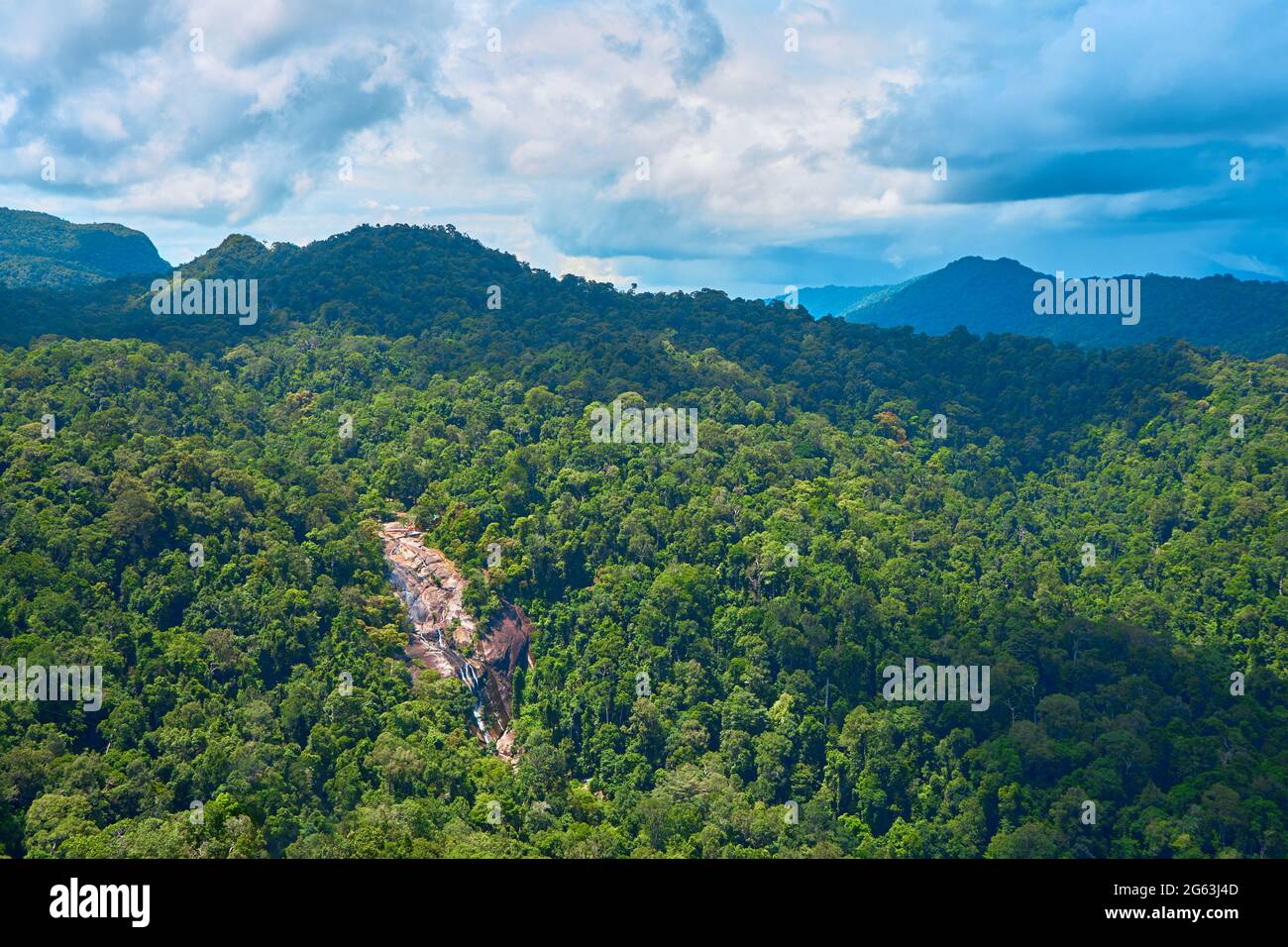 A majestic waterfall flows down the cliff in the dense jungle Stock ...