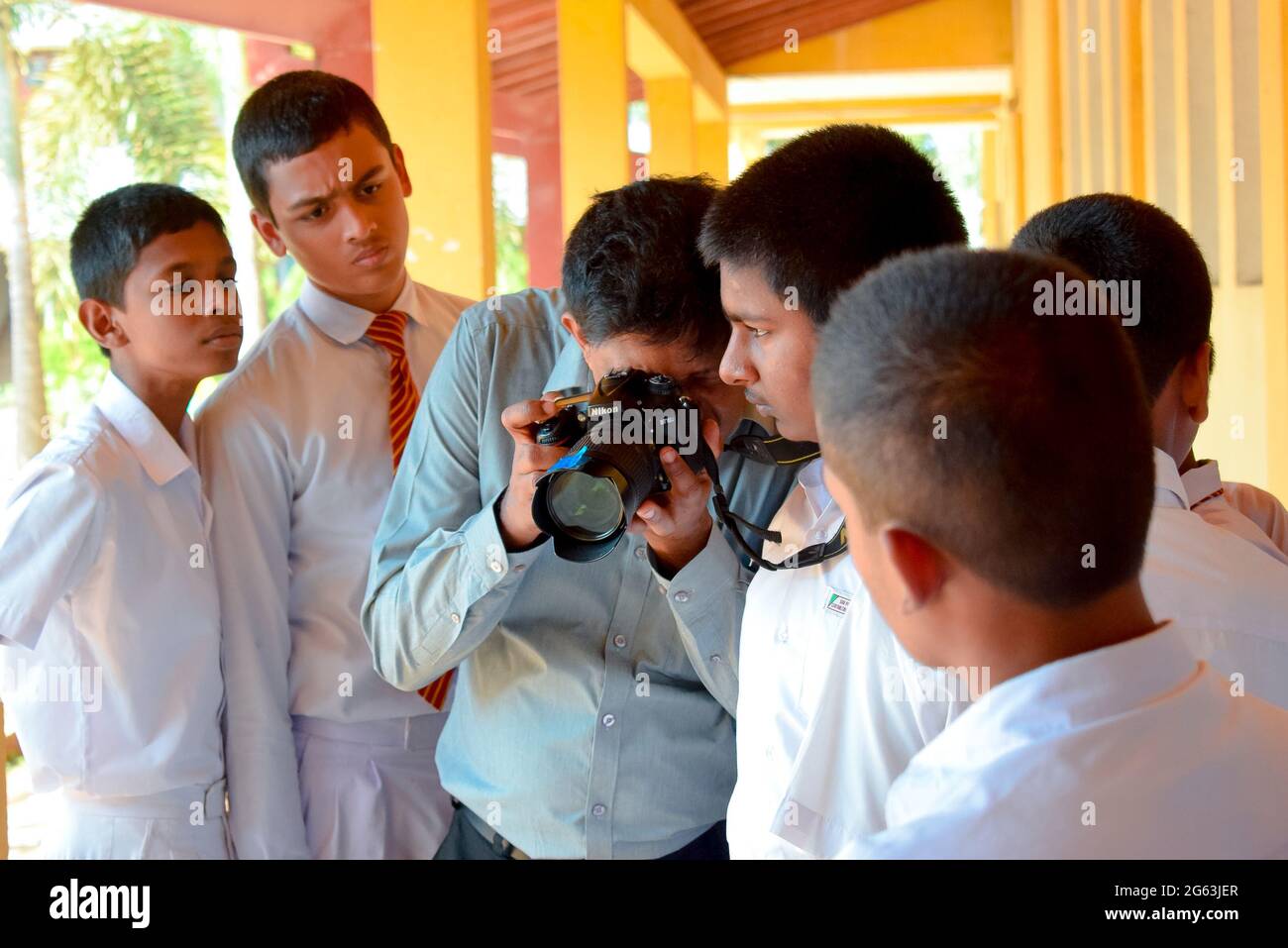 Photography teacher teaching to a school students how to use a dslr ...