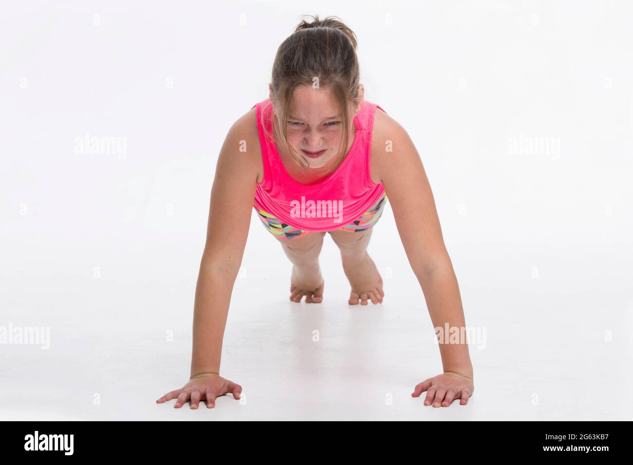 A young tween girl doing push ups with a determined expression Stock ...