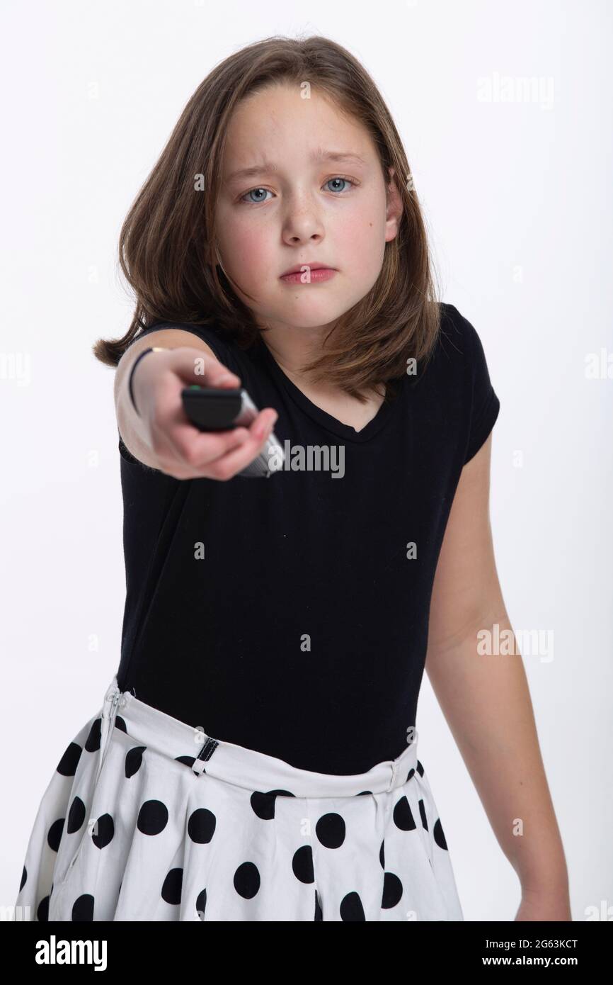 A young tween girl frustrated with a remote control pointing at the ...