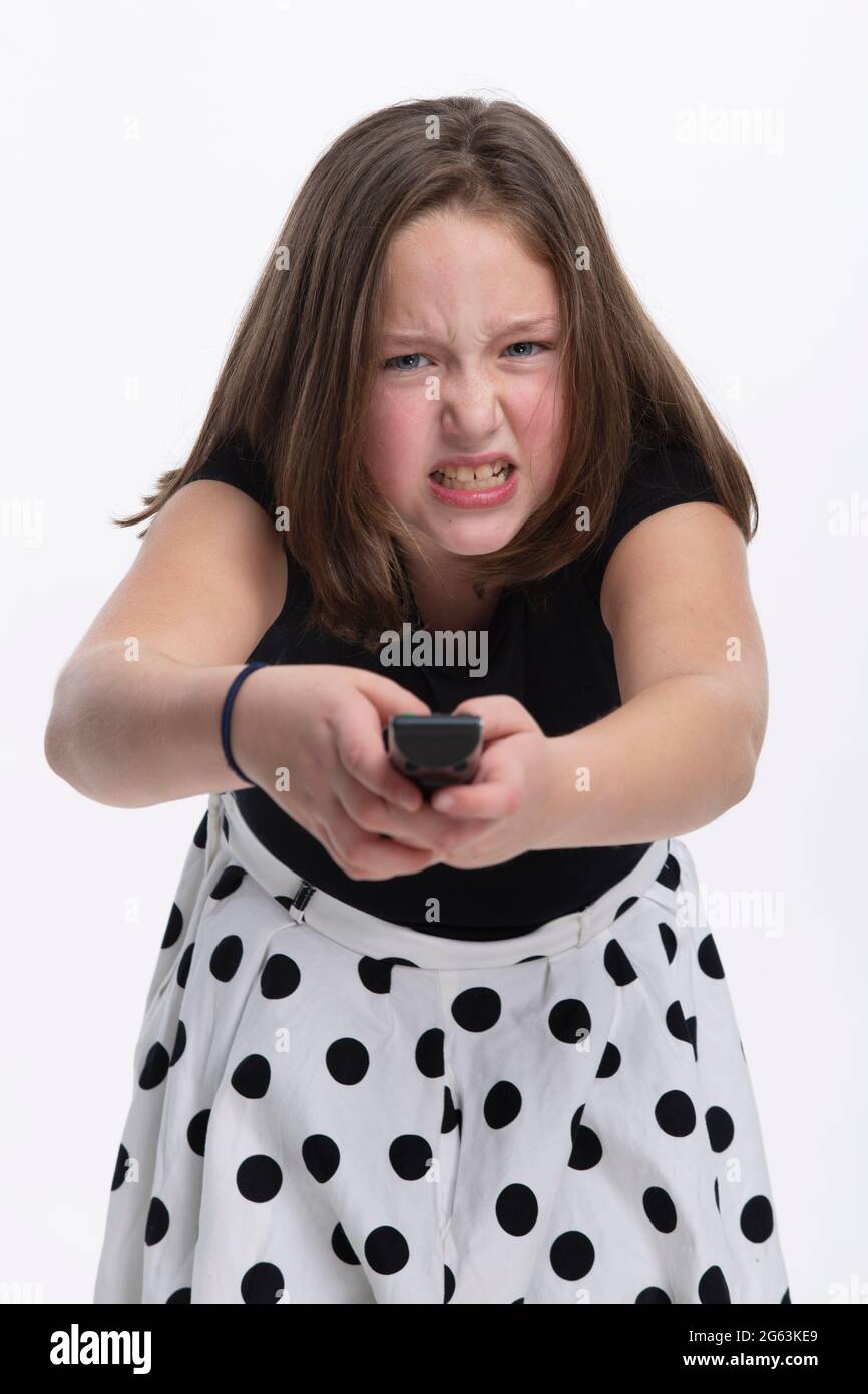 A young tween girl frustrated with a remote control pointing at the ...