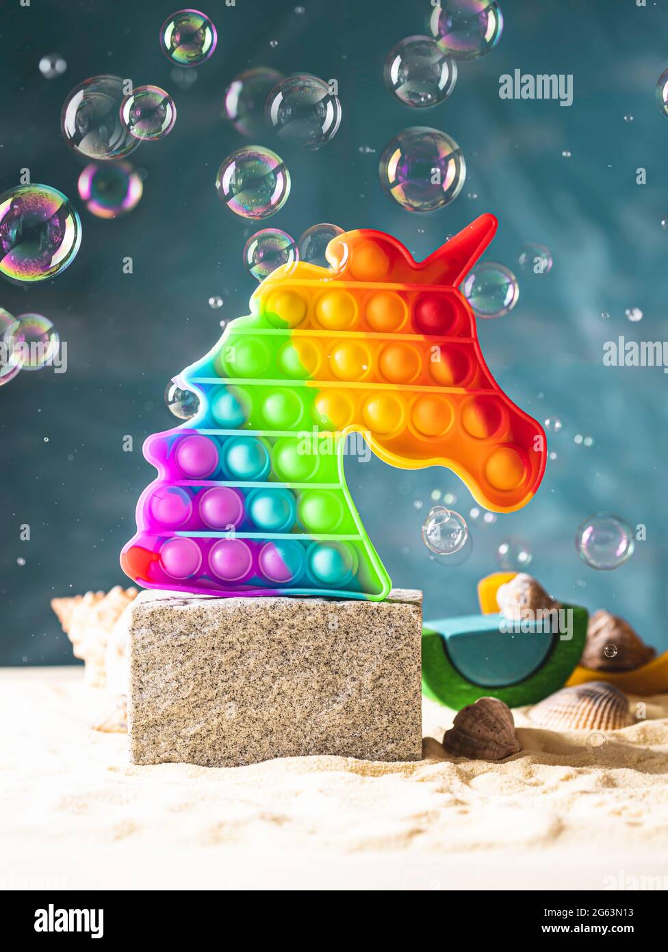 Pop it toy, rainbow colors, in the form of a unicorn on the podium on a ...