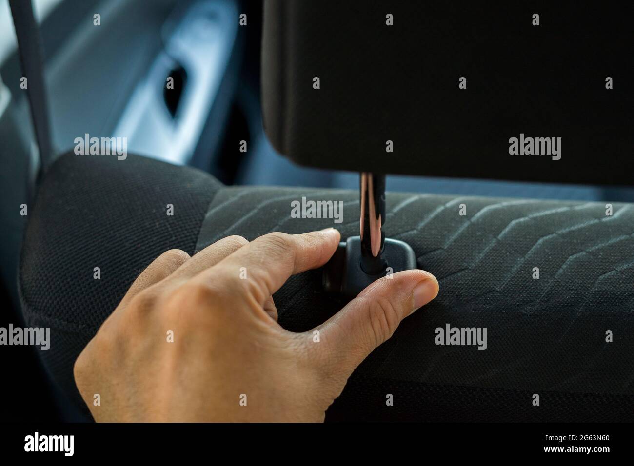 Hand adjusts headrest in car interior. adjusting the seat position in ...