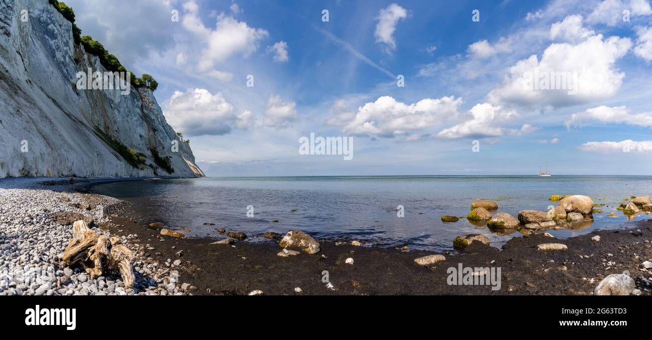 A panorama of tall white chalkstone cliffs dropping into a calm light ...