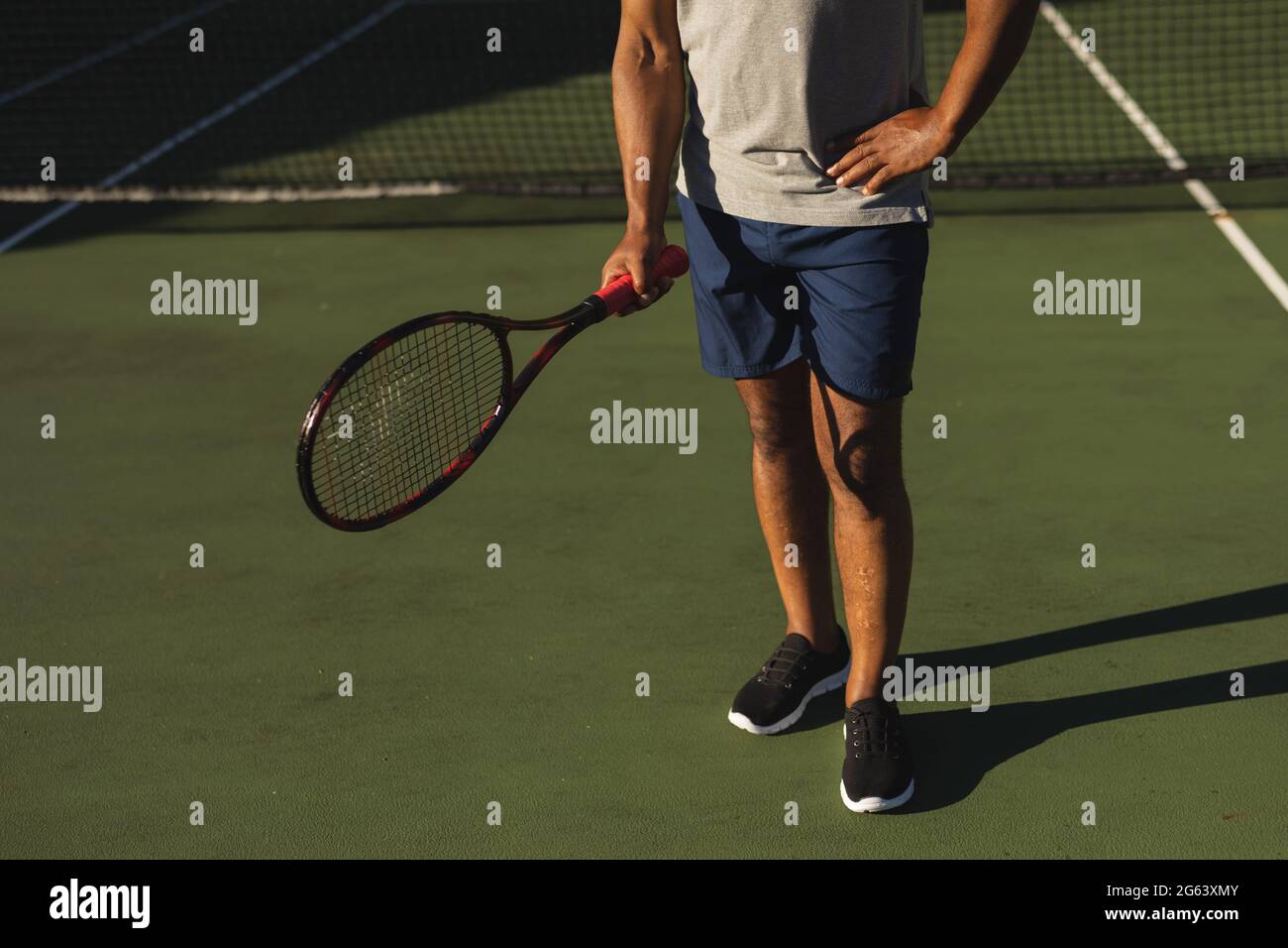 Midsection of senior african american man holding tennis racket on ...