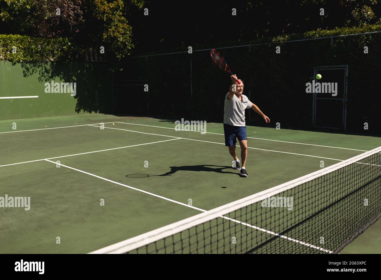 Senior caucasian man playing tennis on court holding tennis racket ...