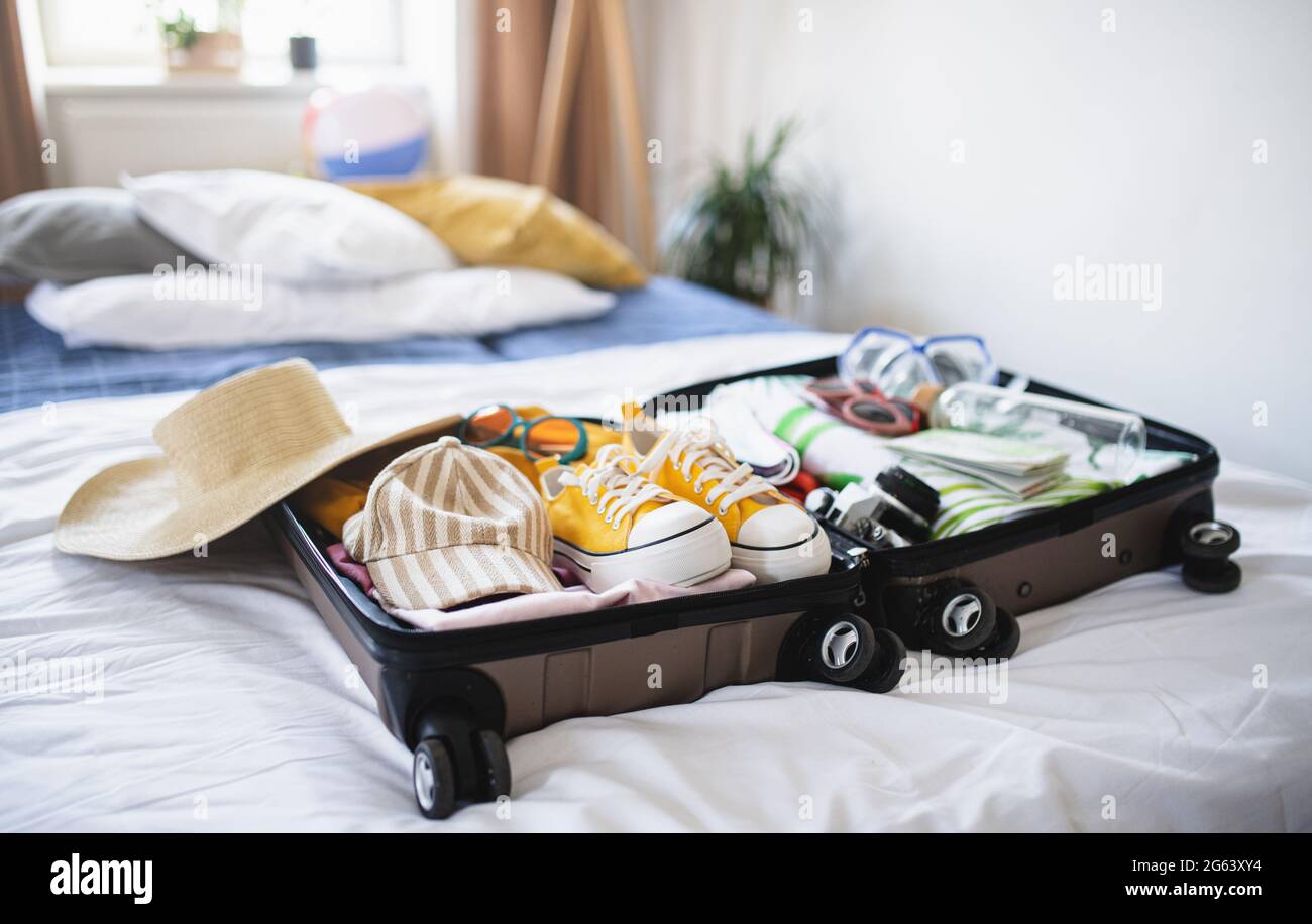 Open suitcase packed for holiday on bed at home, coronavirus concept ...