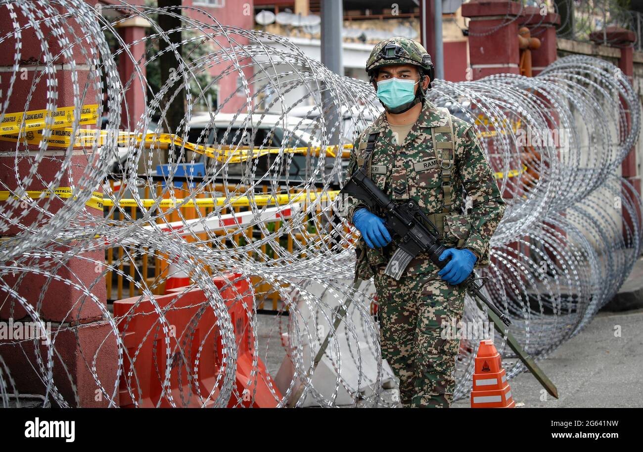 An armed soldier wearing a mask and gloves stands on guard outside a ...