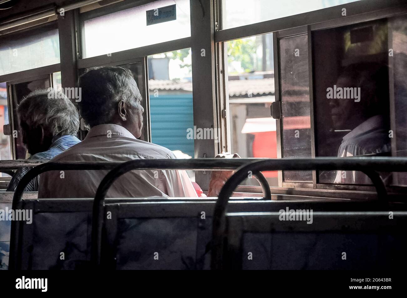 A asian man rides an old bus and looks at architecture out of a ...