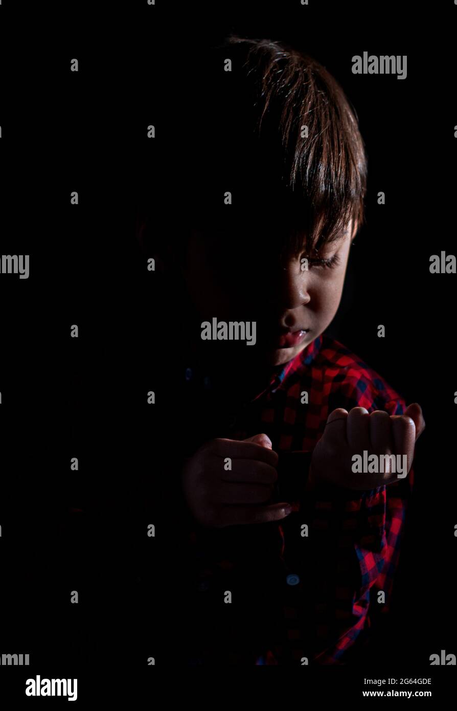 an anguished child in the dark pensive between lights and shadows ...