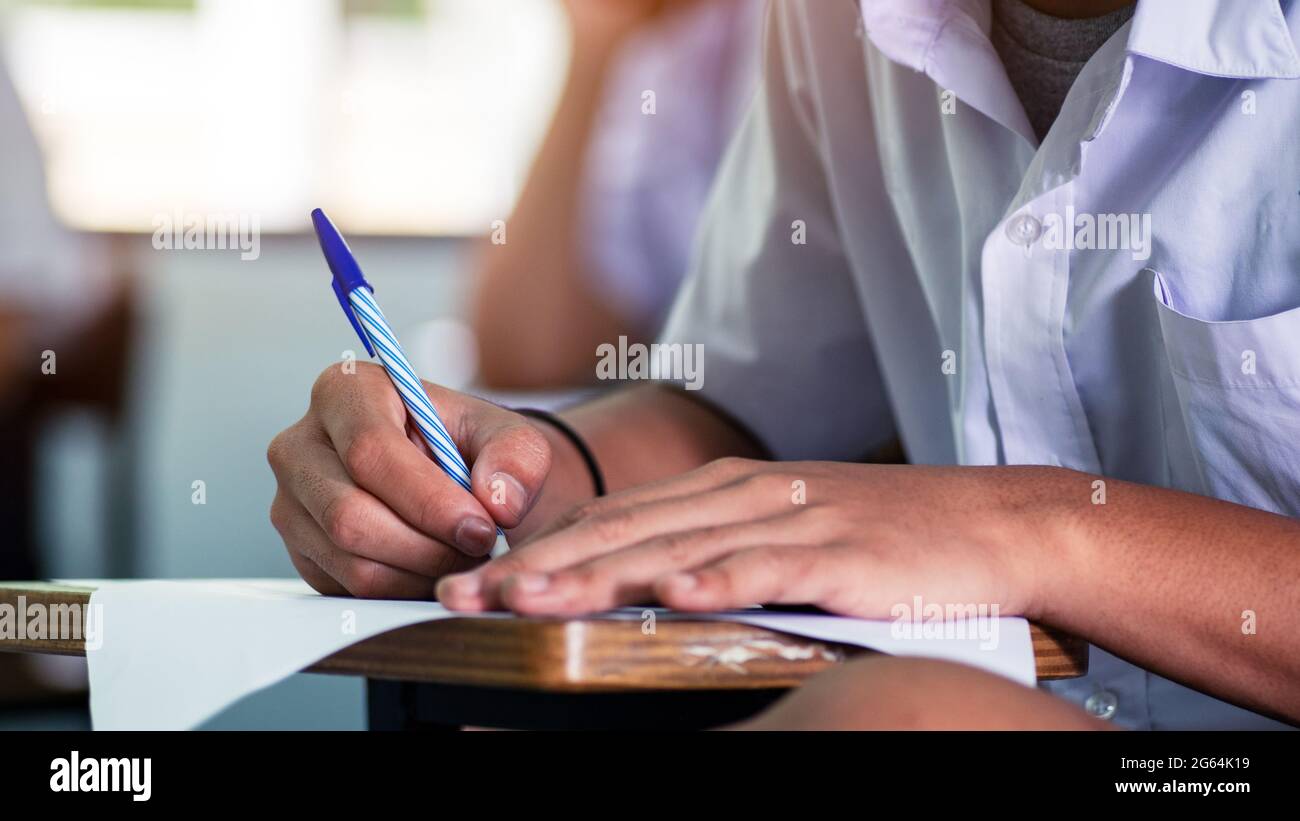 Students writing and reading exam answer sheets exercises in classroom ...