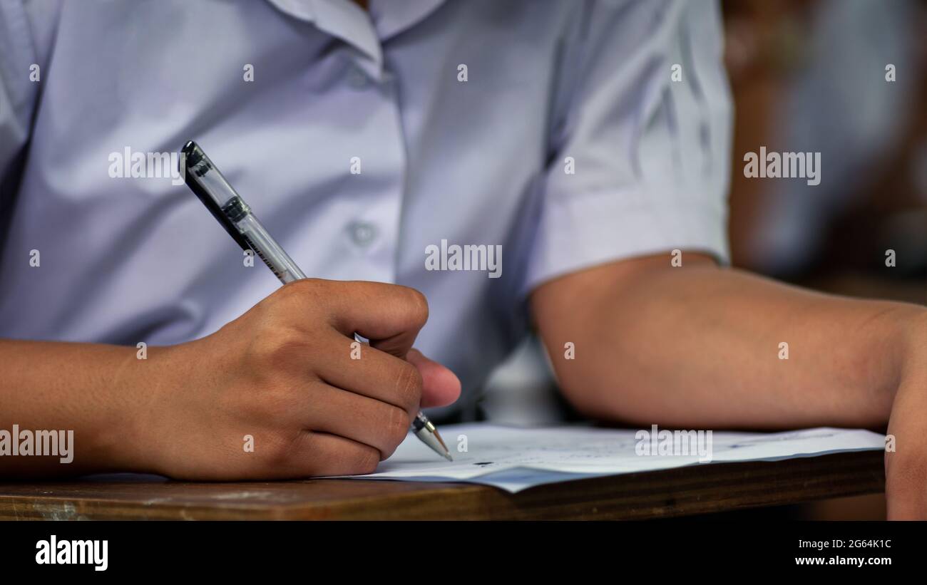 Students writing and reading exam answer sheets exercises in classroom ...