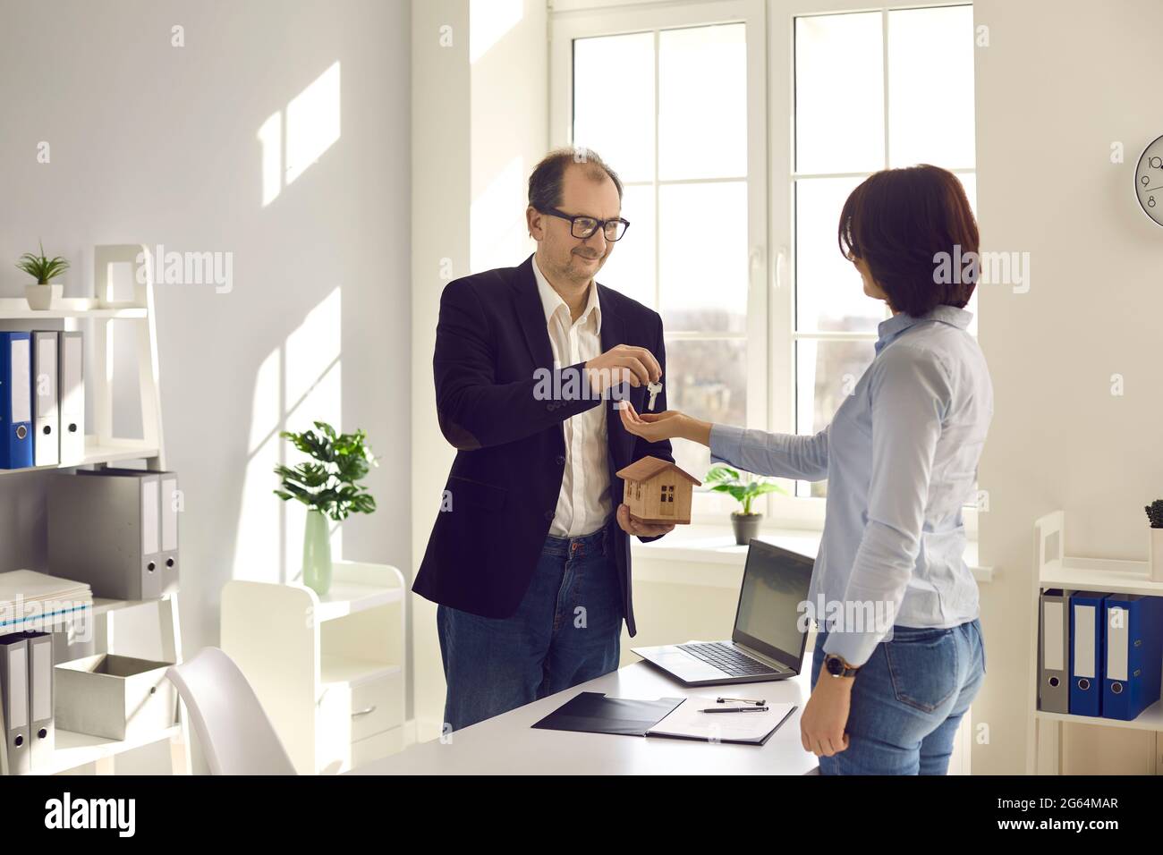 Sale estate agent giving house model and property key to customer at ...