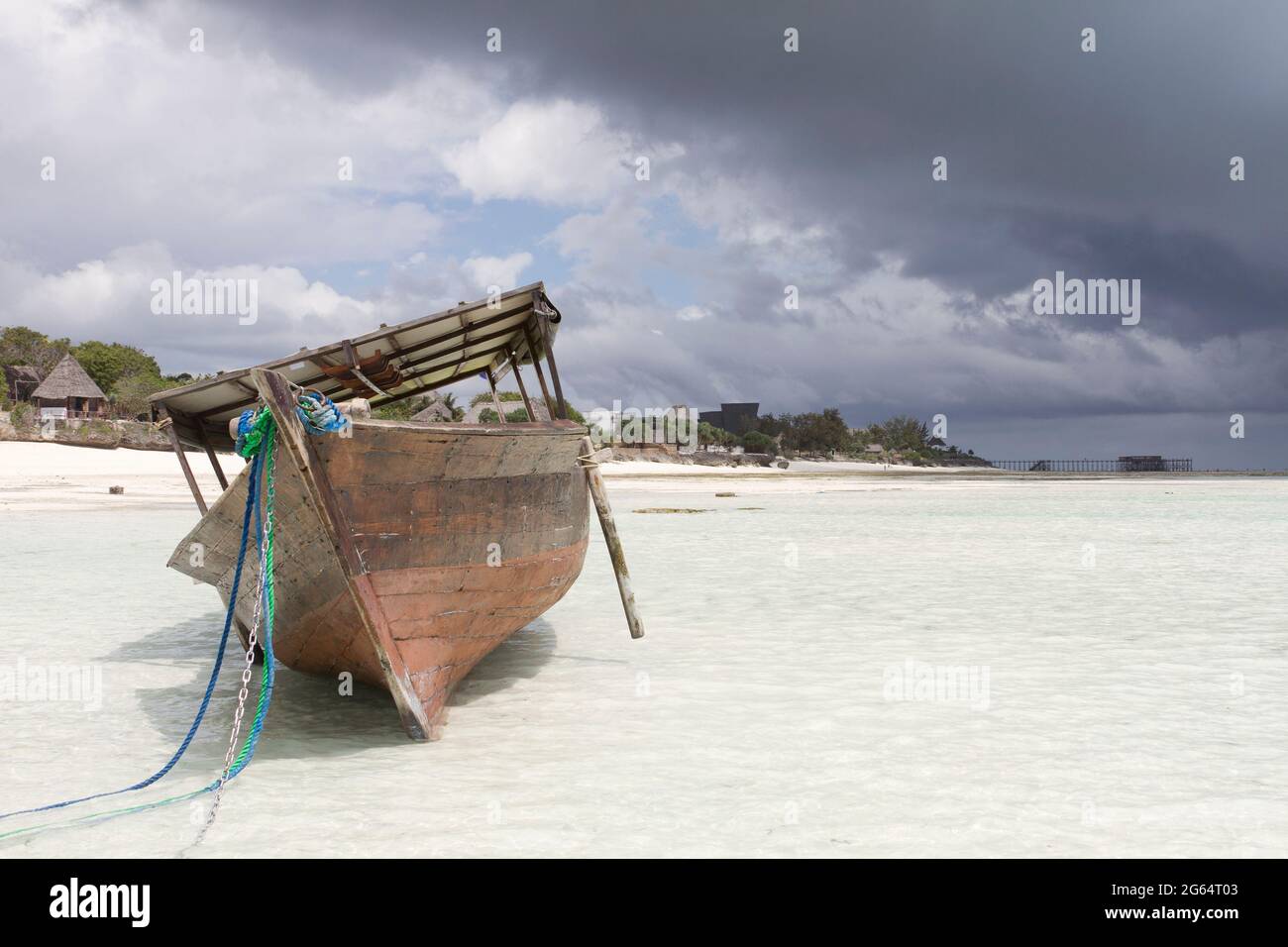 A storm approaches a boat siting on the sand while the tide is out ...