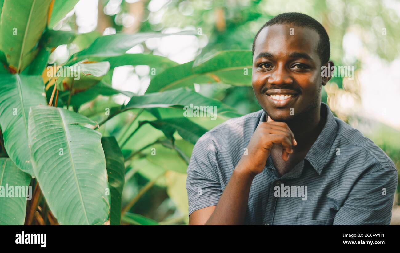 A charming, friendly african man who stands smiling with the green ...