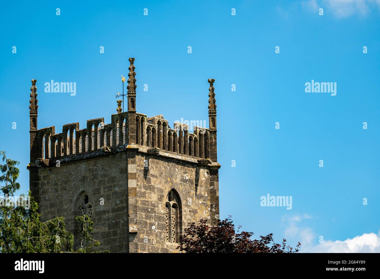 Ancient church spire and trees captured against bright blue sky Stock ...