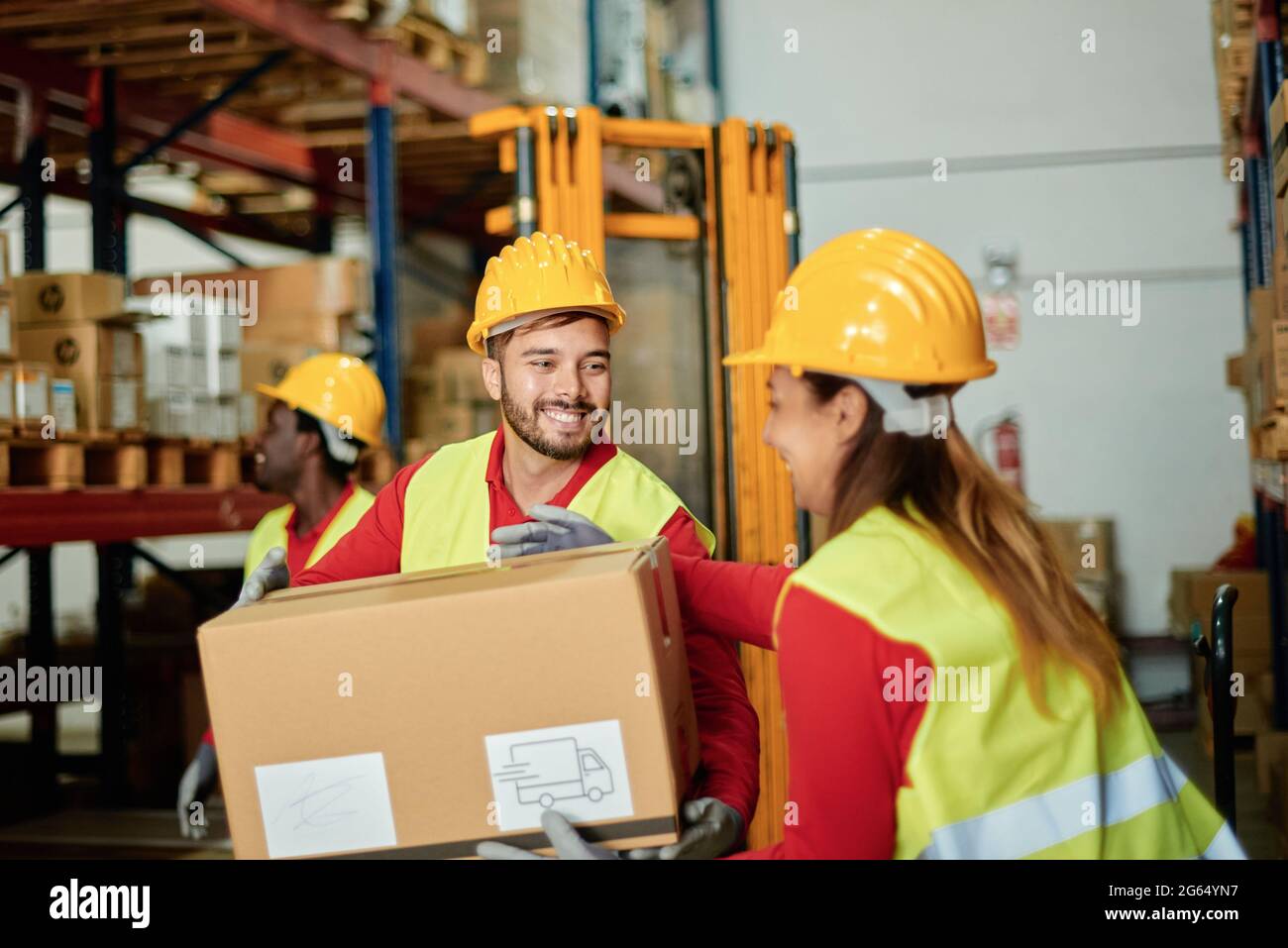 Positive warehouse workers carrying heavy box Stock Photo - Alamy