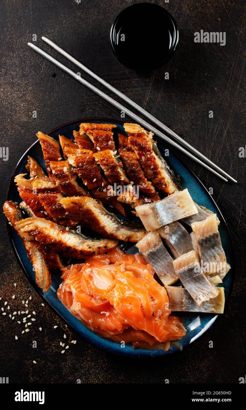 herring eel and salmon on black plate, fish on plate Stock Photo - Alamy