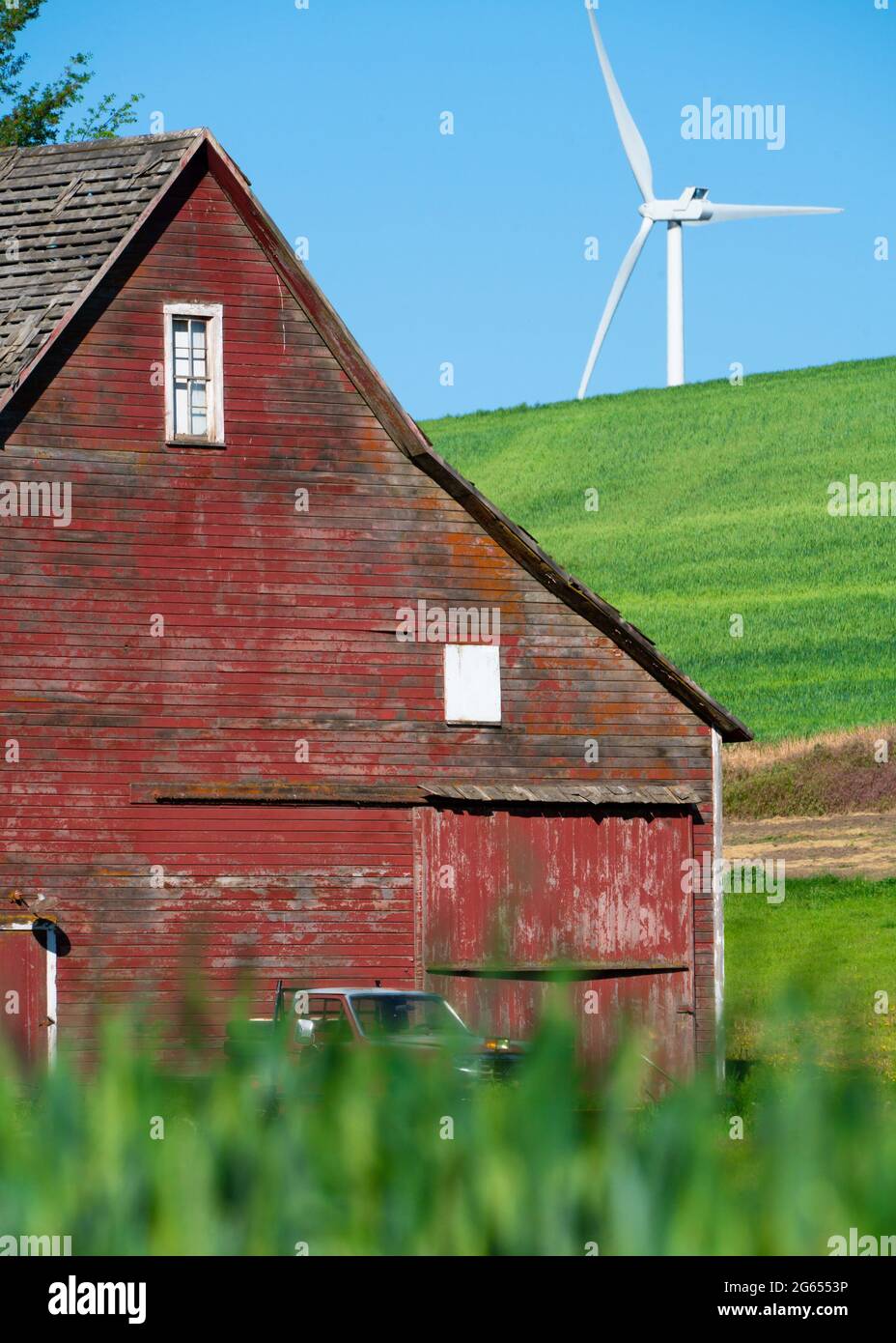 Rustic wooden red barn with modern wind turbines in the background seen ...