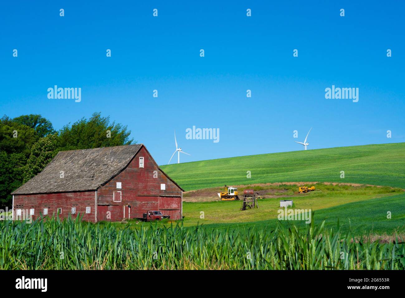 Rustic wooden red barn with modern wind turbines in the background seen ...