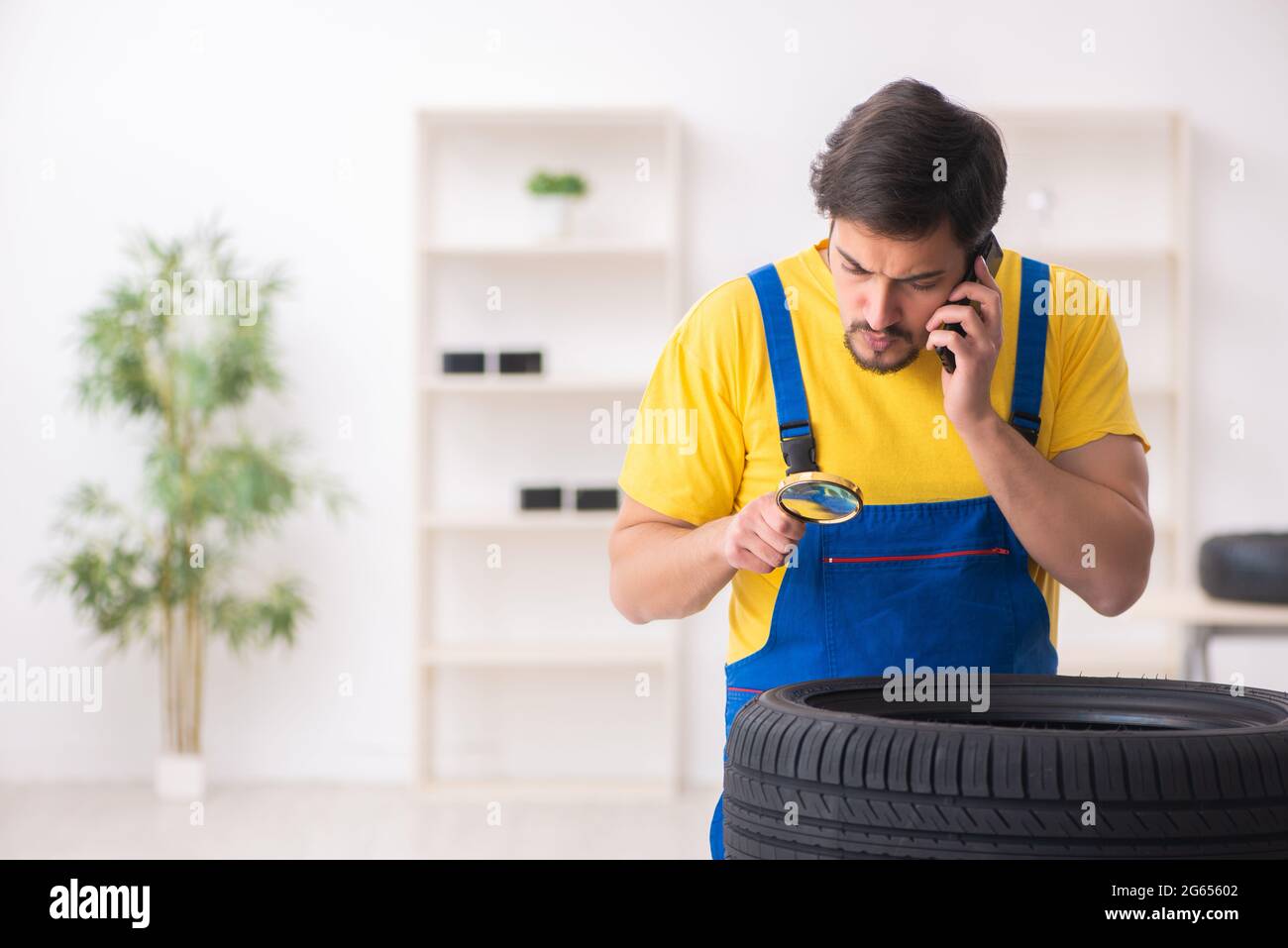 Young garage worker with tyre at workshop Stock Photo - Alamy