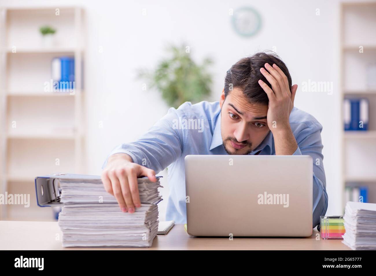 Young employee and too much work in the office Stock Photo - Alamy