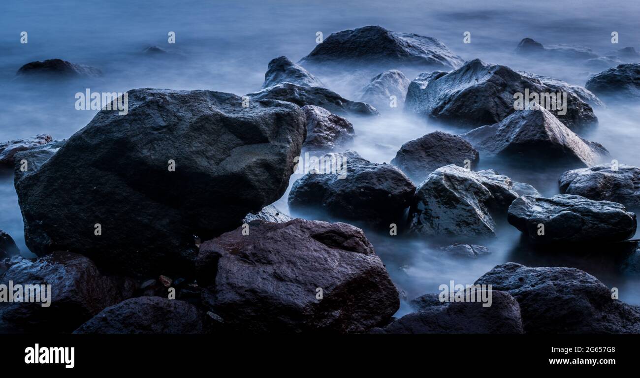 Rocks and flowing waves Stock Photo - Alamy