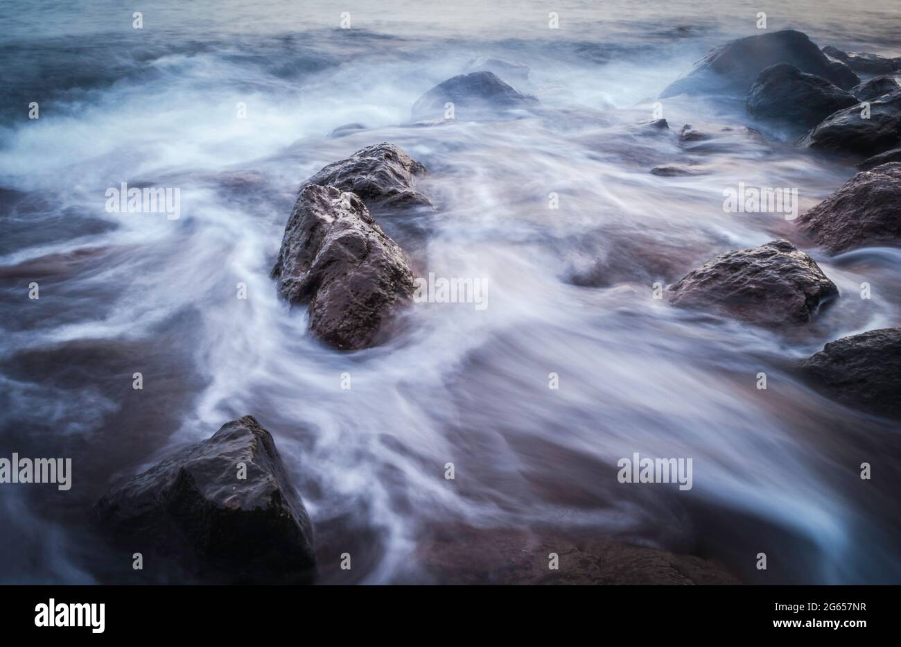 Rocks and flowing waves Stock Photo - Alamy